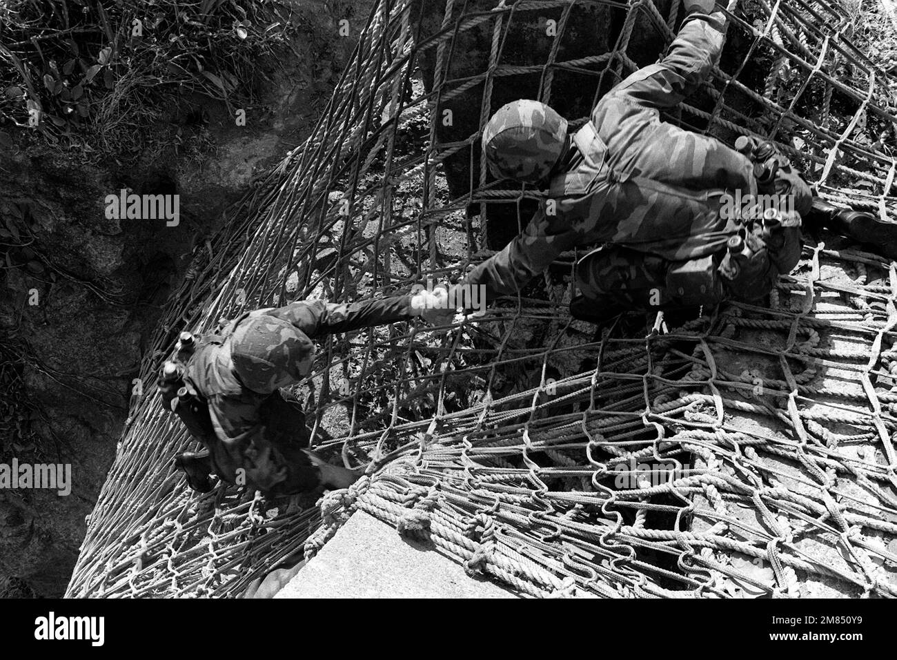 A member of the 1ST Battalion, 5th Marines, helps another Marine climb ...