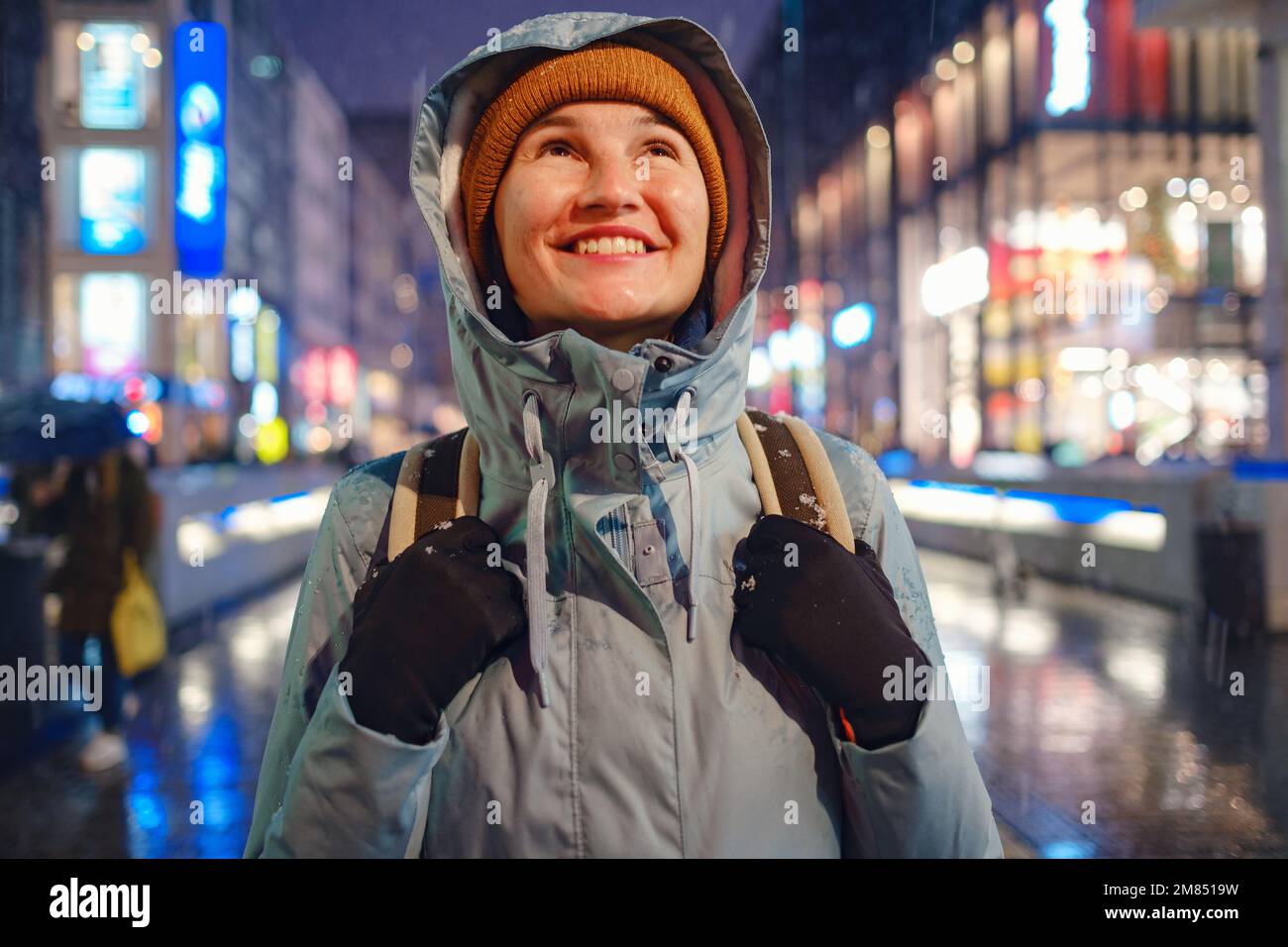 snowfall woman in a blue jacket and yellow hat christmas outside, city ...