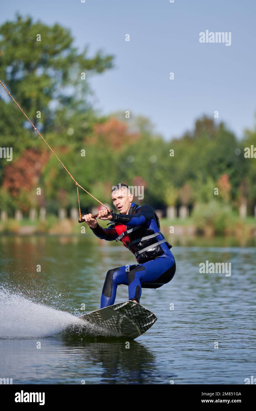 Wakeboarder surfing on lake. Young surfer having fun wakeboarding in ...