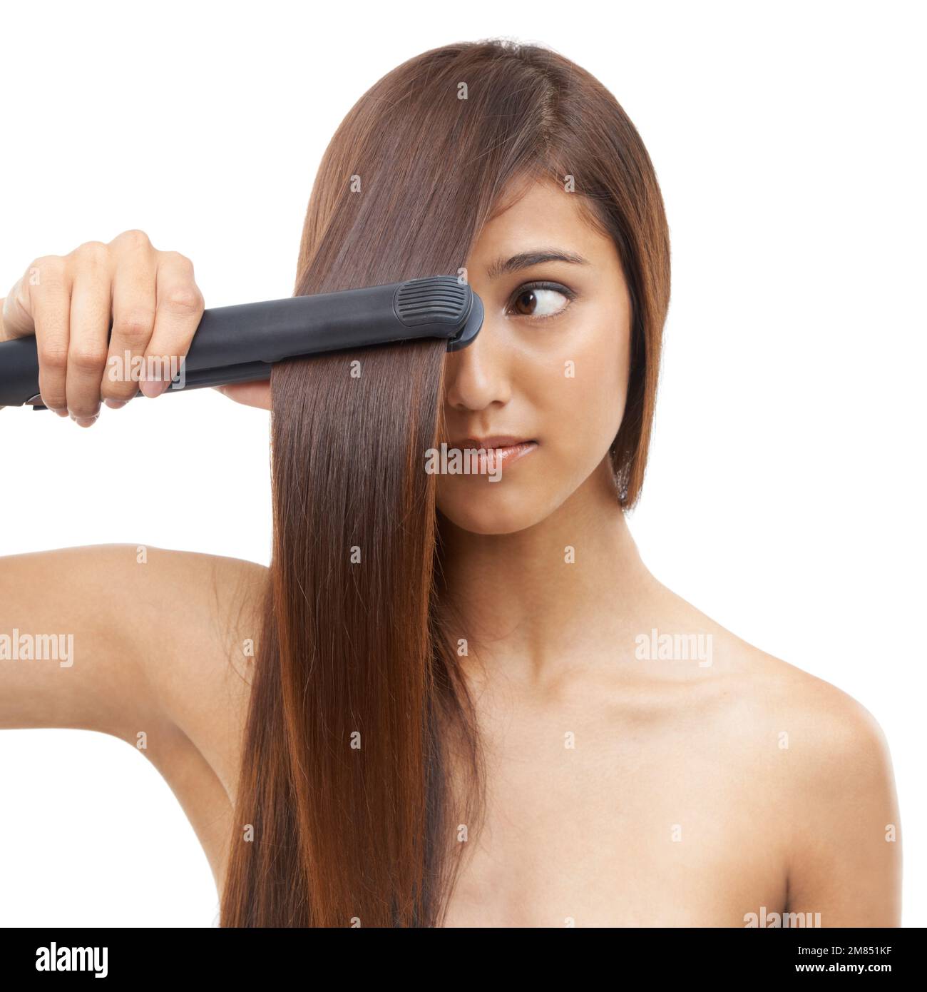 Straightening her hair for a great date. A young woman straightening ...