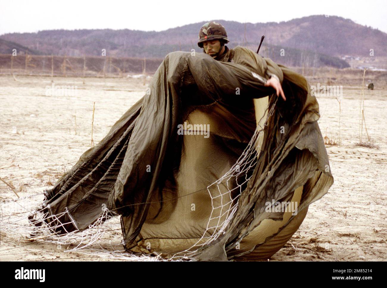 A paratrooper from Co. B, 1ST Special Forces, gathers his parachute ...