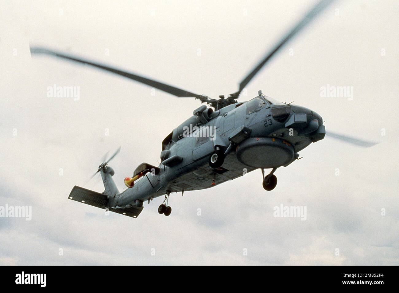 An SH-60B Sea Hawk helicopter hovers above the flight deck of a ship ...