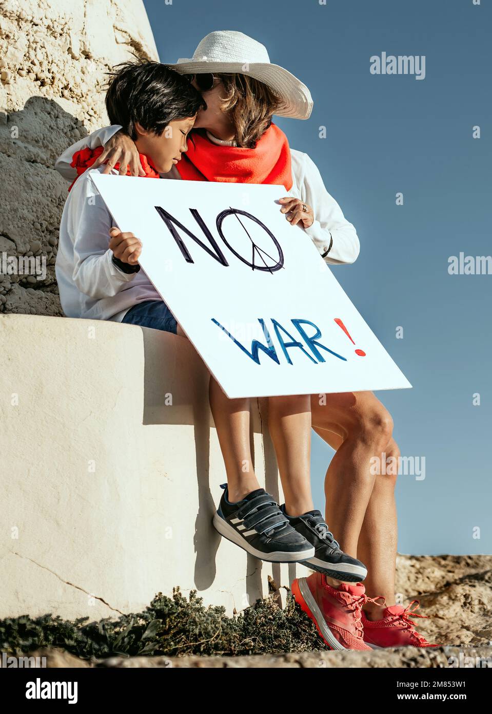 A mother comforts her Asian son in front of a bunker, while holding a ...