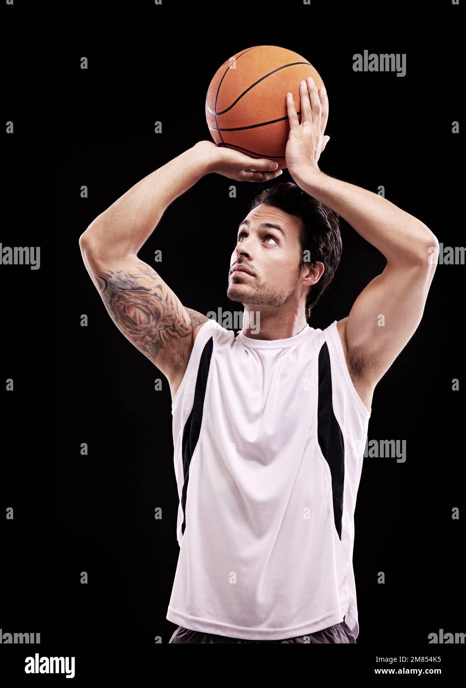 Shooting hoops. A young man about to throw a basketball against a black ...