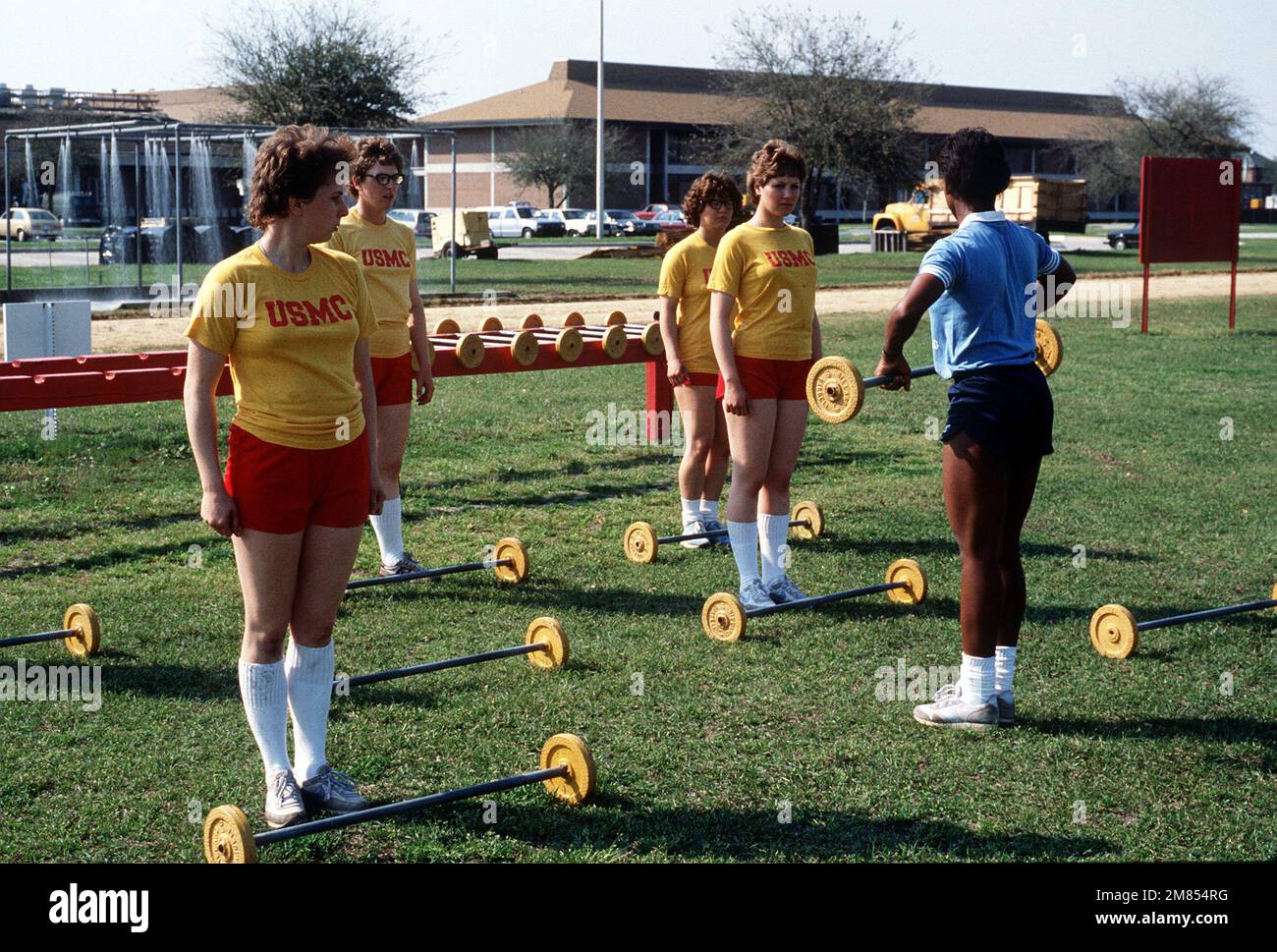 A drill instructor demonstrates curls to female Marine recruits during ...