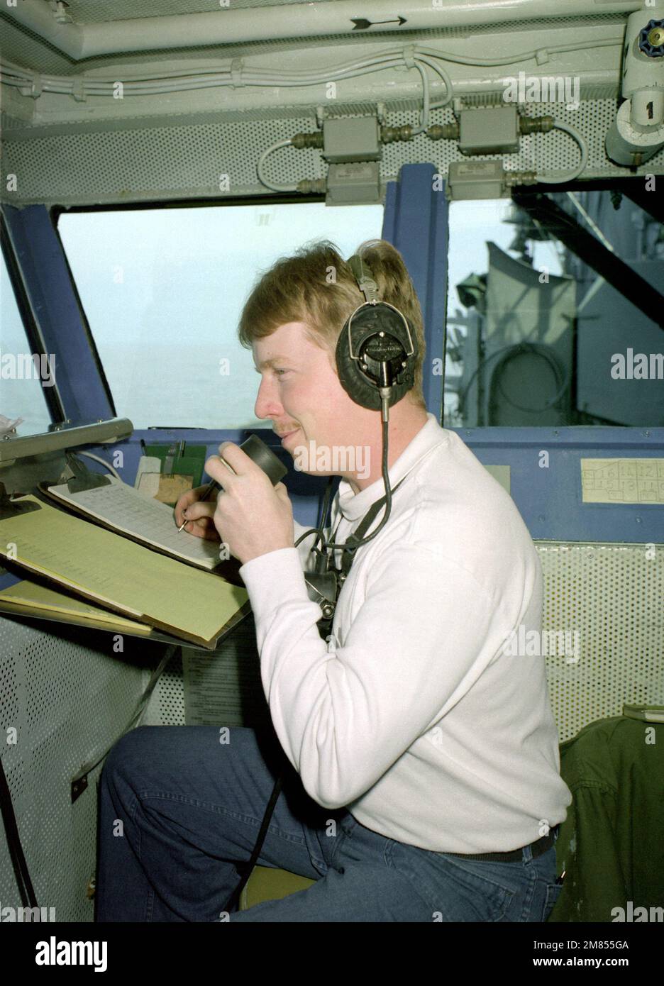 A crewman aboard the aircraft carrier USS SARATOGA (CV-60) lists the ...