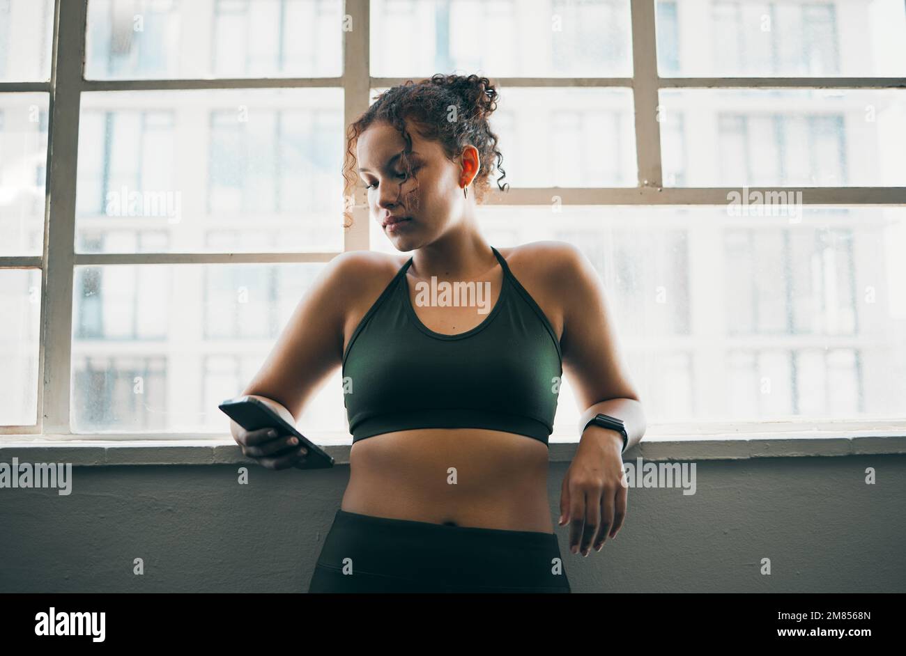 Idea, phone and exercise with a sports woman by a window, standing in ...