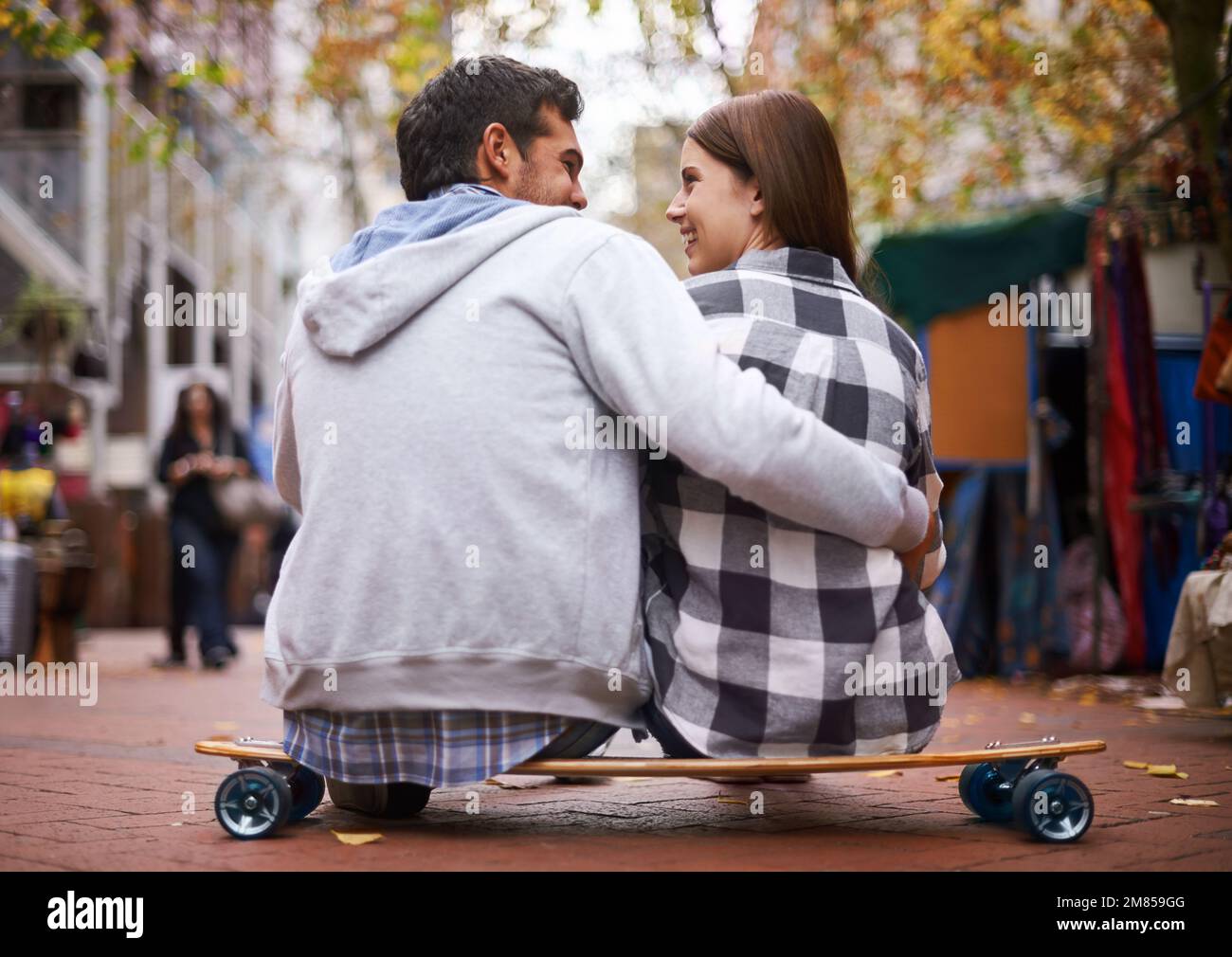 Romantic break from longboarding. REarview shot of a young couple ...