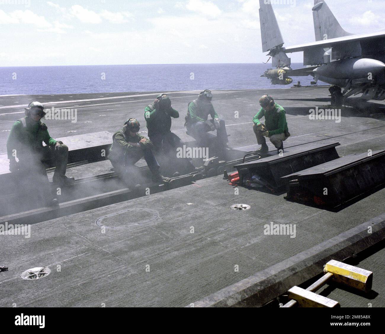 Catapult crewmen stand by as a catapult is reset for launching during ...