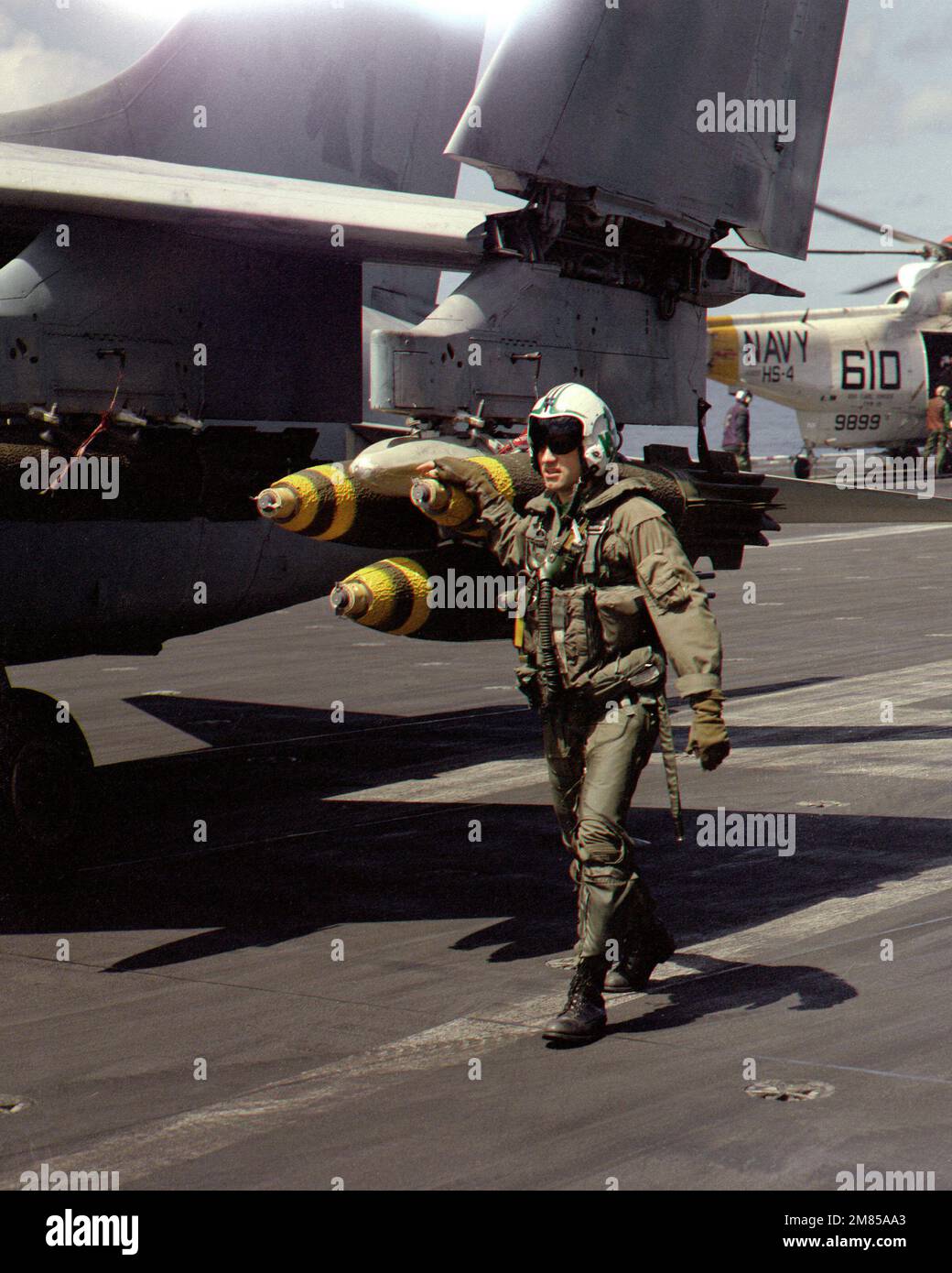 A pilot walks beside an A-7E Corsair II aircraft armed with Mark 82 500 ...