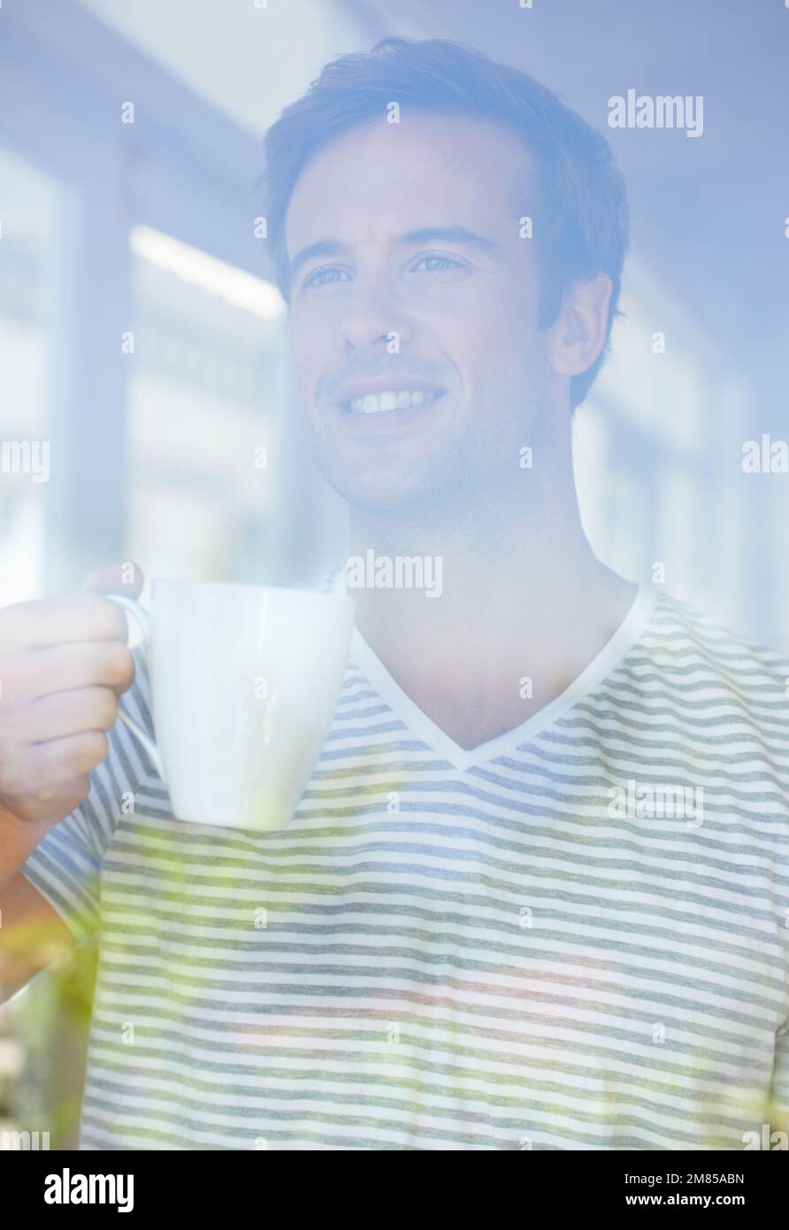 Peering through the glass. A young man standing and looking out of a ...