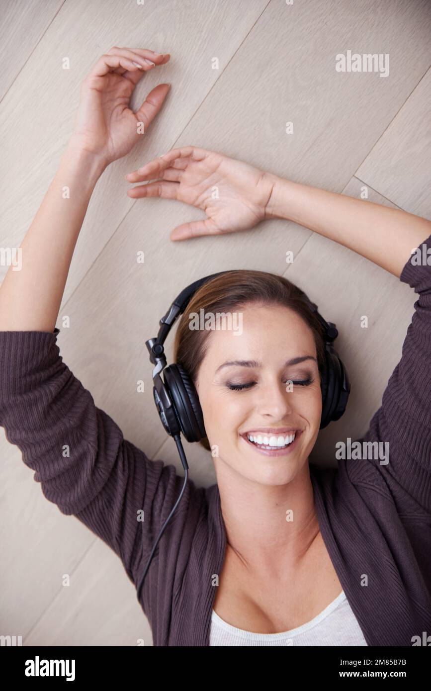 Smooth sounds. A young woman smiling as she listens to music over her ...