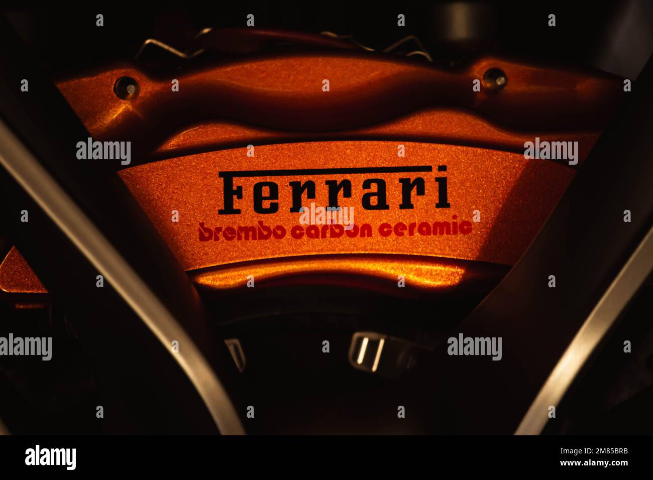 A closeup of a Ferrari Carbo Ceramic brake caliper in a metallic gold ...
