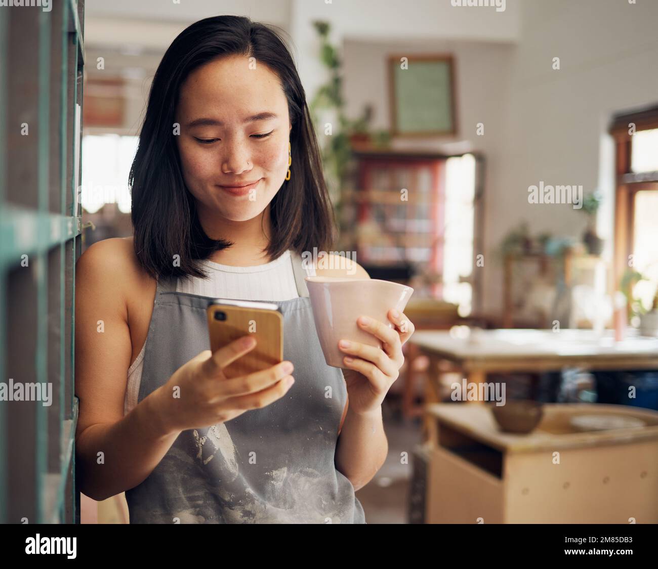 Artist woman, phone and reading chat with coffee, smile and focus on ...