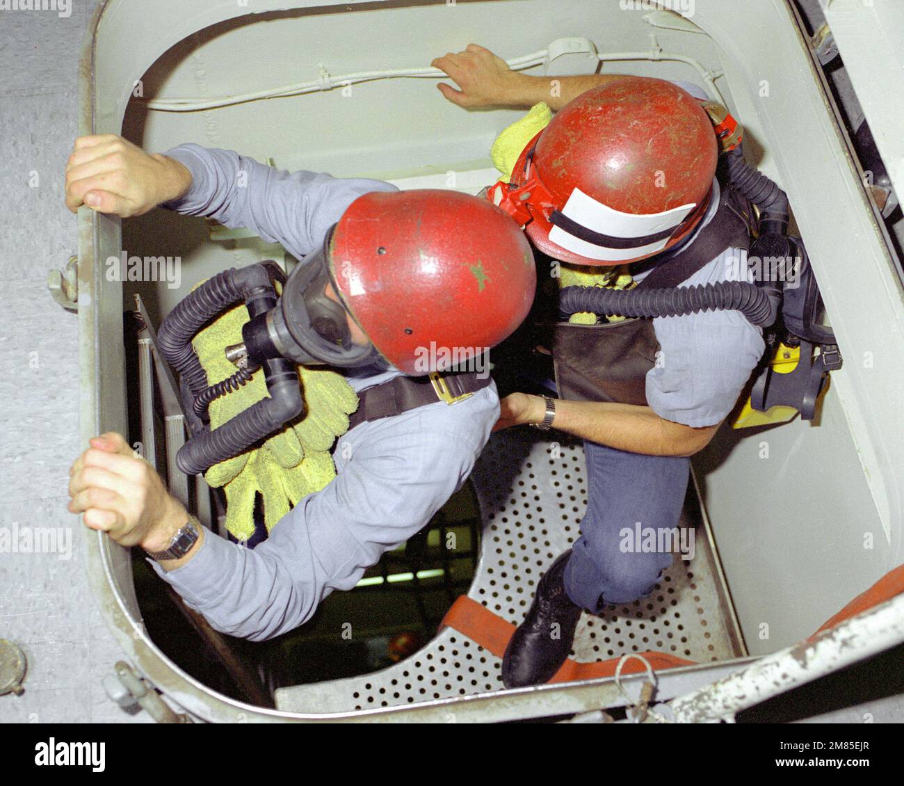 Members of a damage control party emerge from an open hatch during a ...