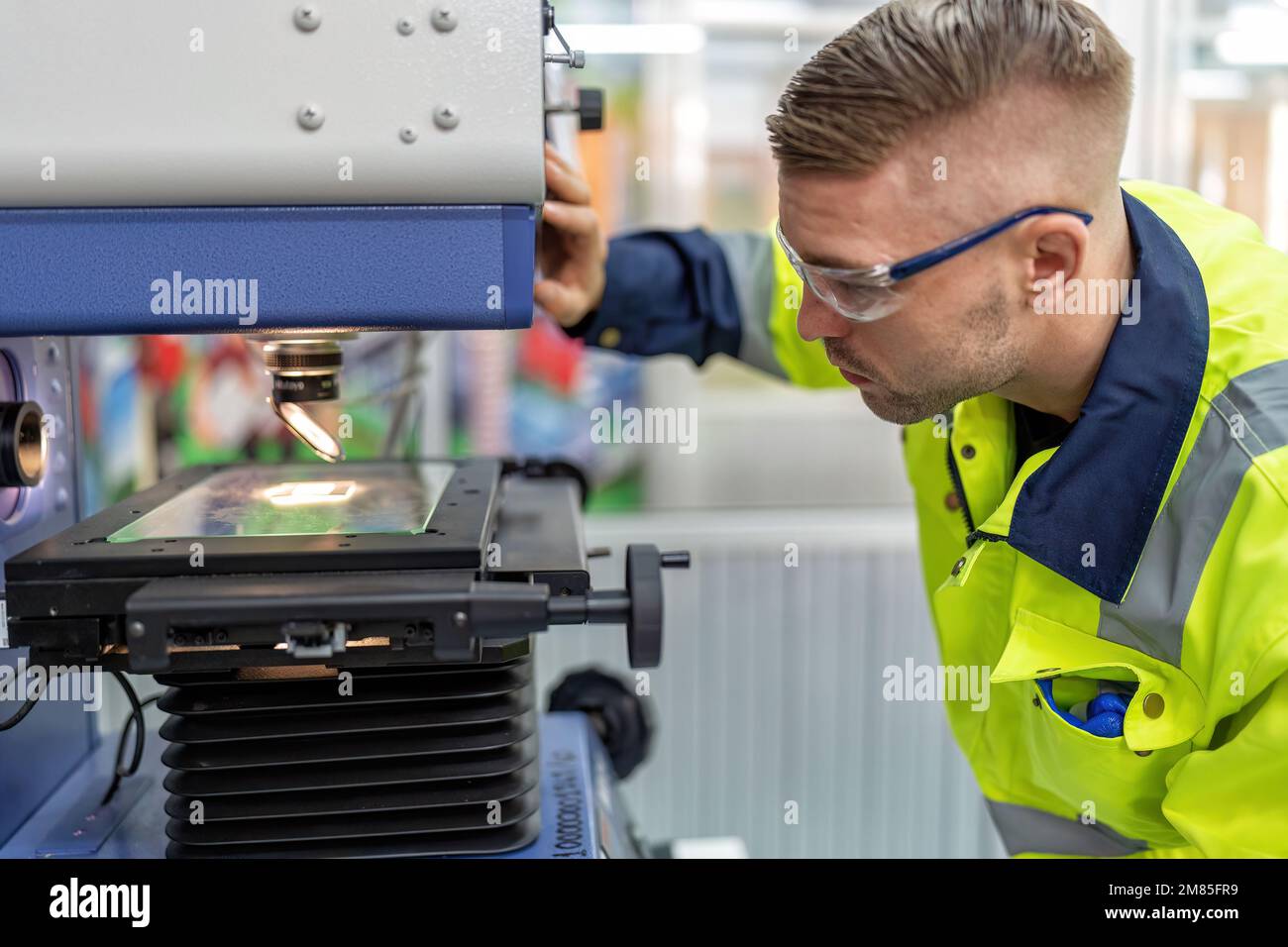 Engineer sitting in robot fabrication room use measuring microscope ...