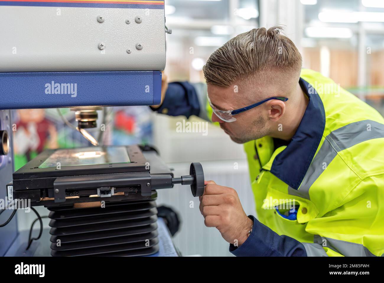 Engineer sitting in robot fabrication room use measuring microscope ...