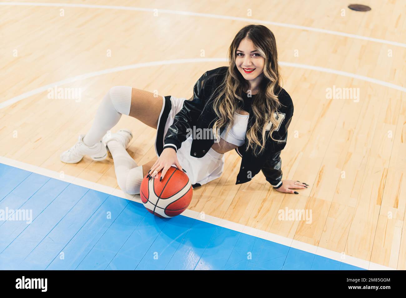 Young cheerleader sitting confidently on the arena floor with ...