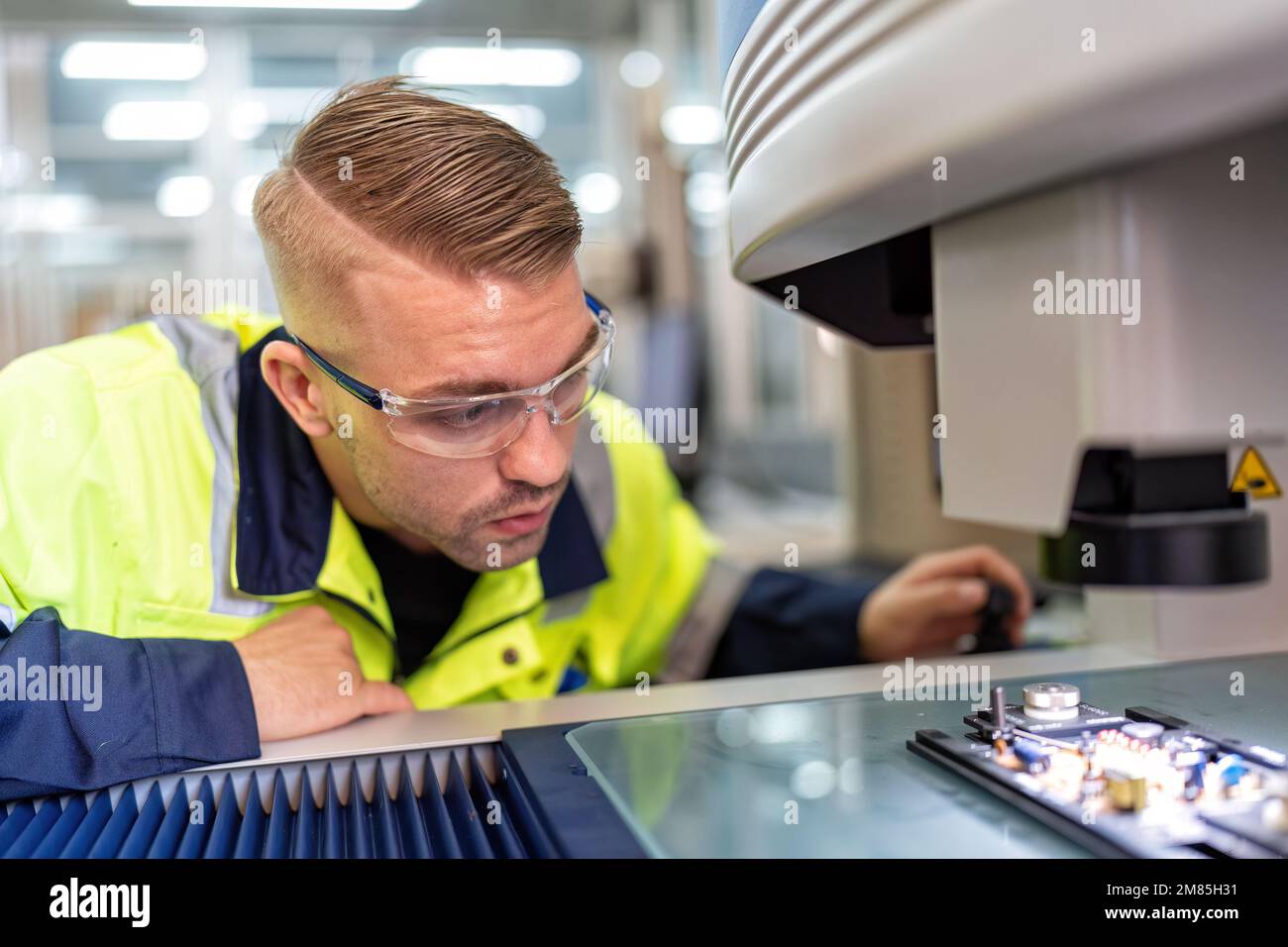 Engineer sitting in robot fabrication room use measuring microscope ...