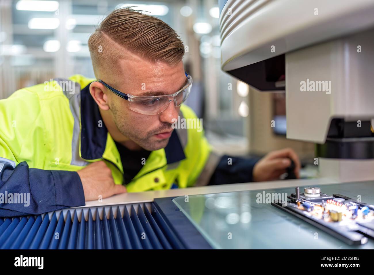 Engineer sitting in robot fabrication room use measuring microscope ...
