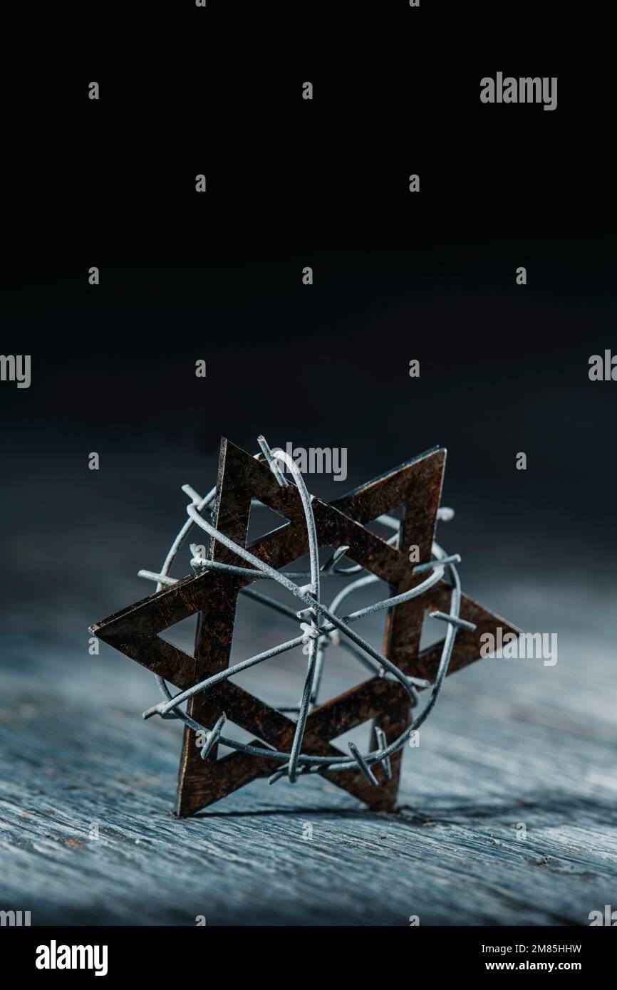 an old star of david tied with some barbed wire on a gray rustic wooden ...