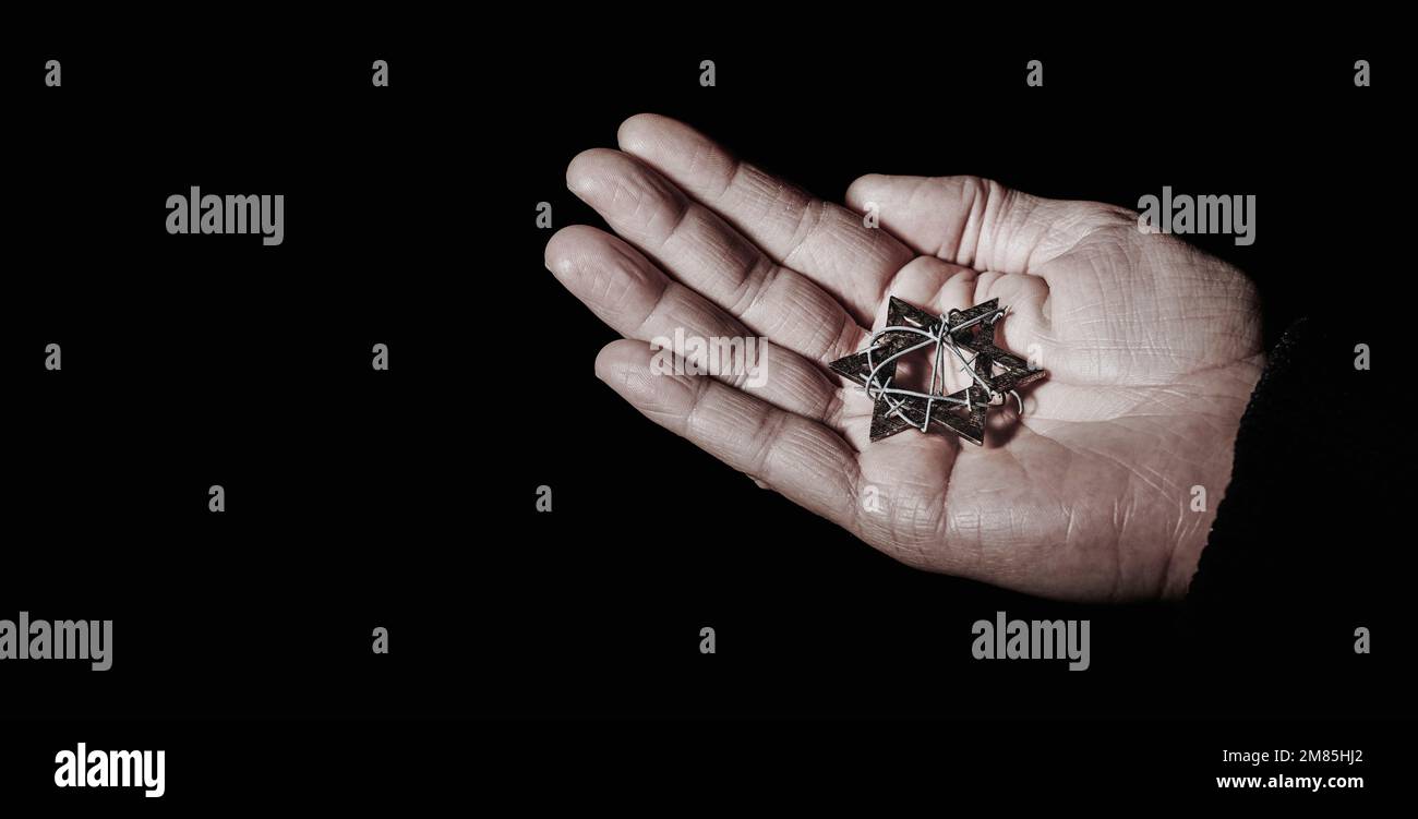 a star of david tied with some barbed wire in the hand of a man, on a ...