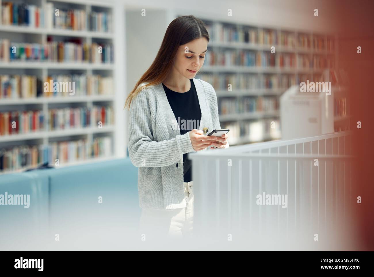 Library, phone and woman student networking on social media, mobile app ...