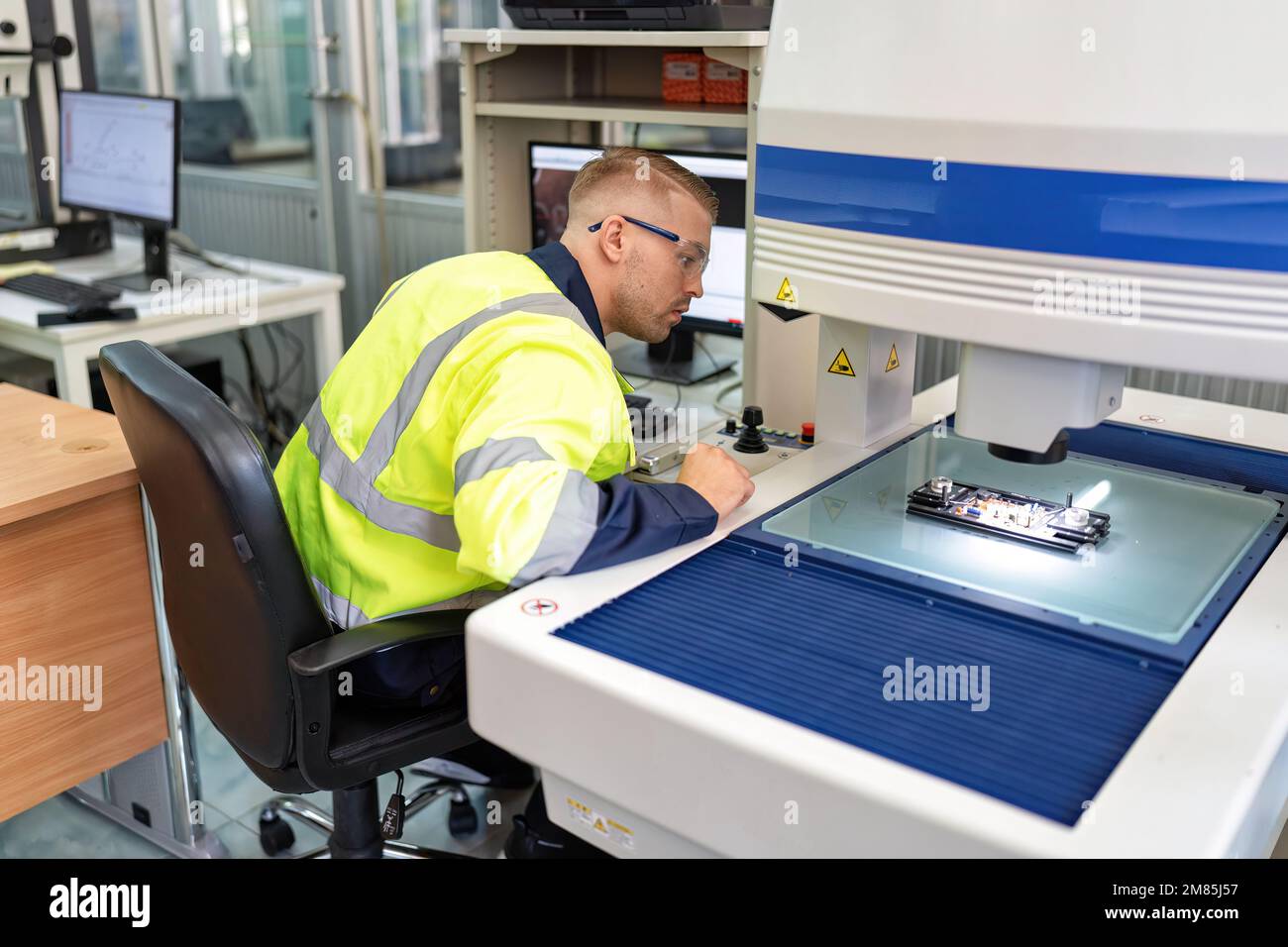 Engineer sitting in robot fabrication room use measuring microscope ...