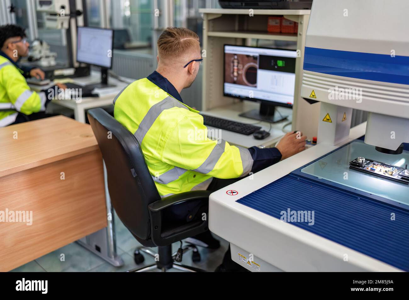 Engineer sitting in robot fabrication room use measuring microscope ...