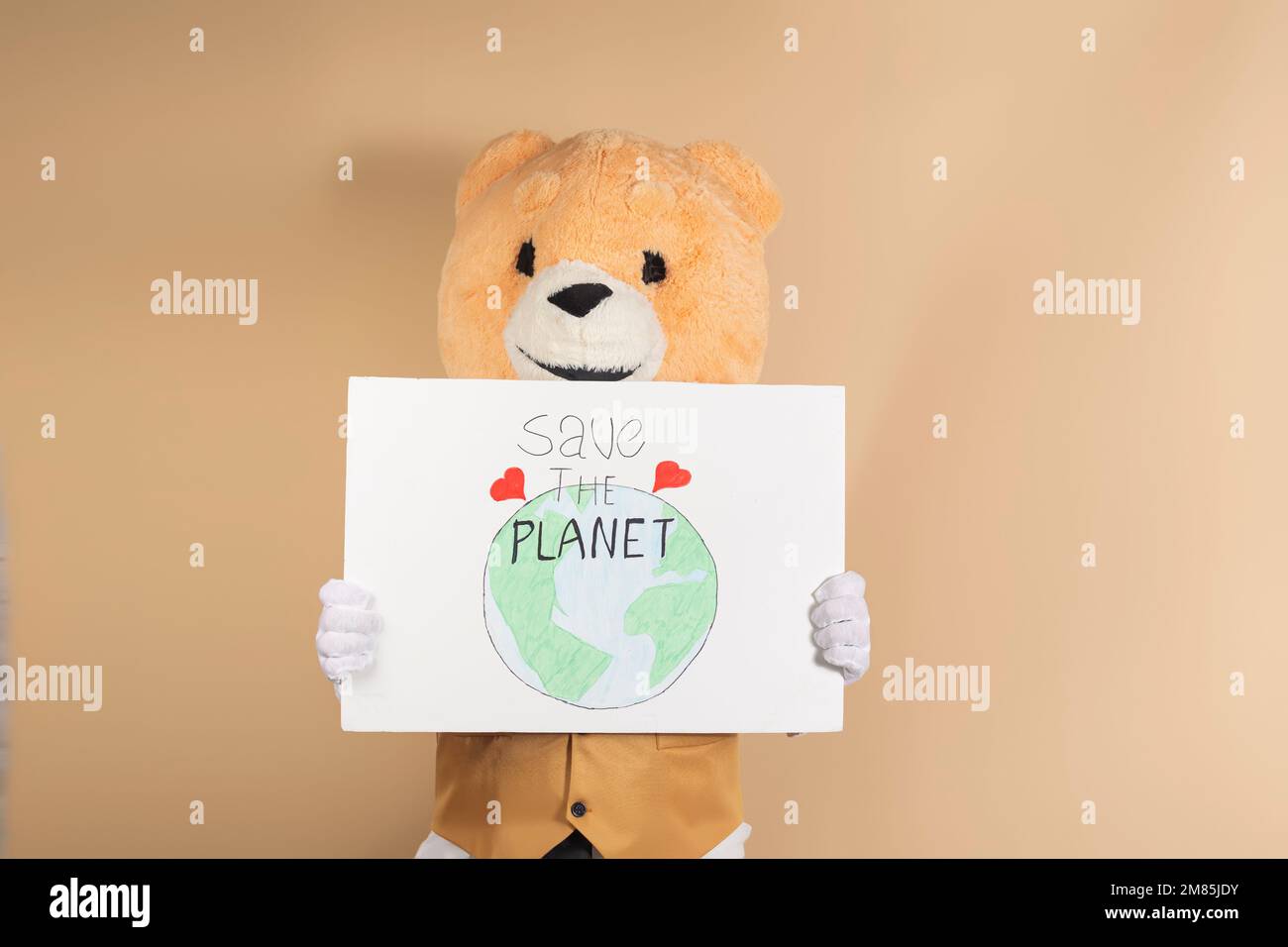 Man wearing a teddy bear mask on a yellow background, holding a ...