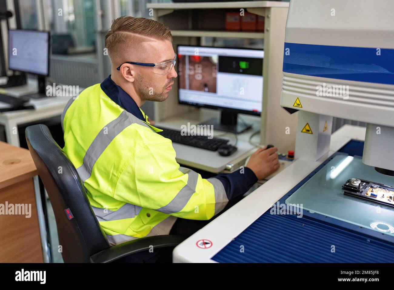 Engineer sitting in robot fabrication room use measuring microscope ...