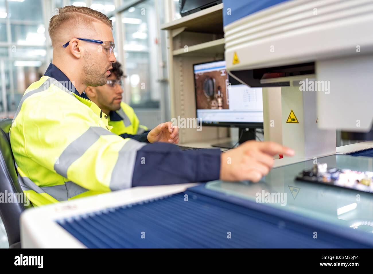Engineer sitting in robot fabrication room use measuring microscope ...