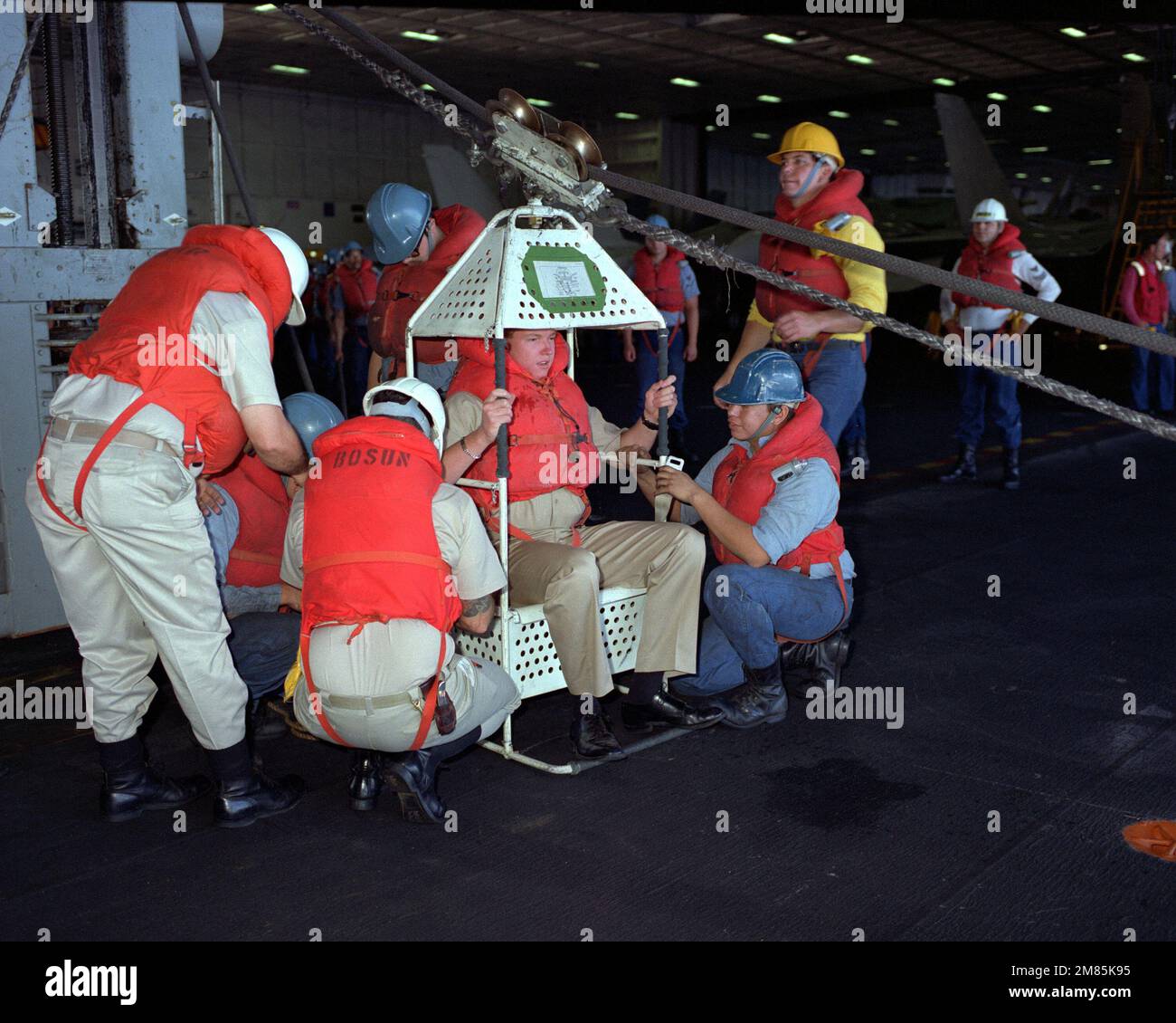 Crew members secure an officer in a transfer chair connected to a ...