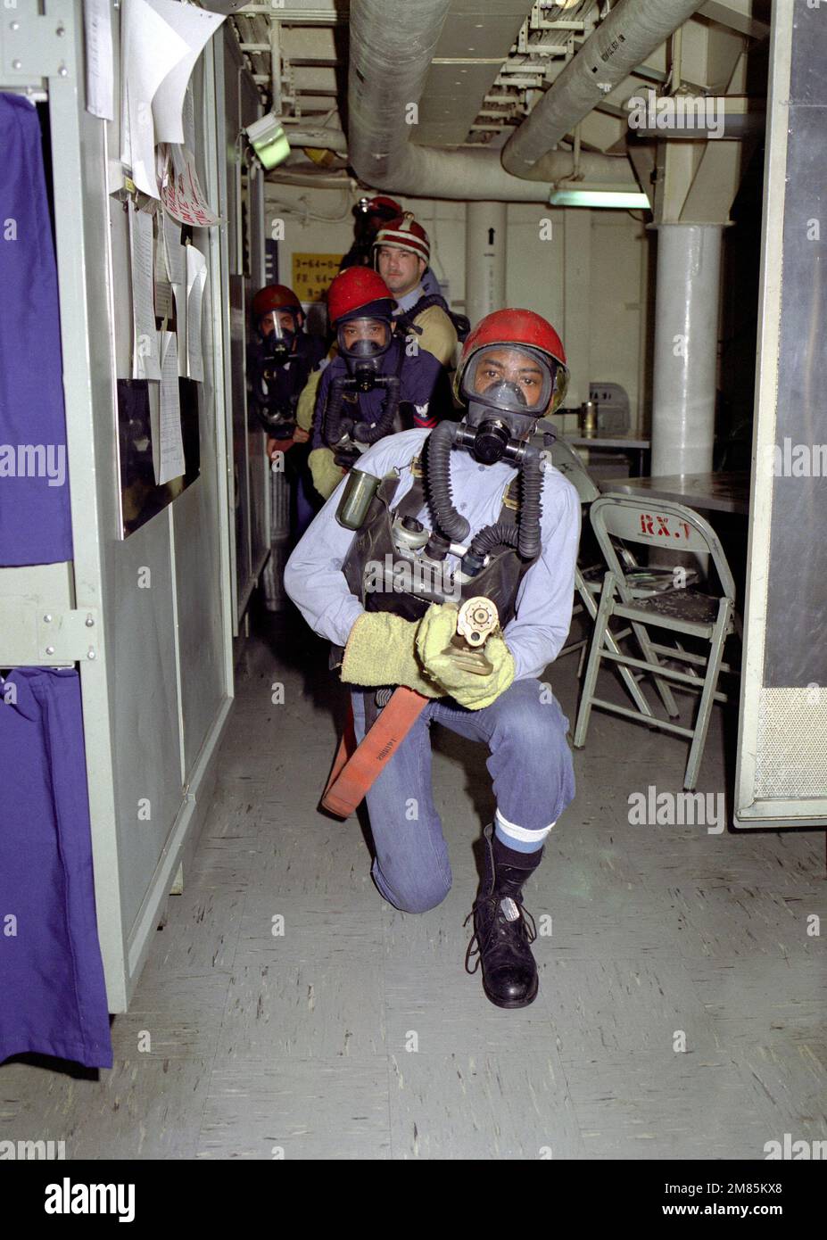 Members of a damage control party wear oxygen breathing apparatus while ...
