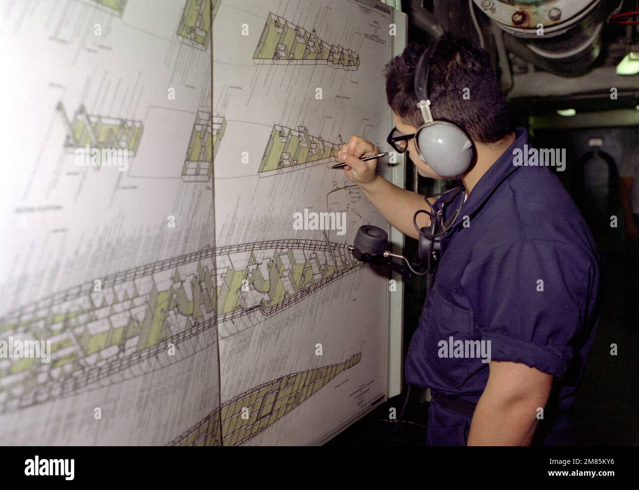 A crewman makes notes on a deck chart as he receives reports from ...