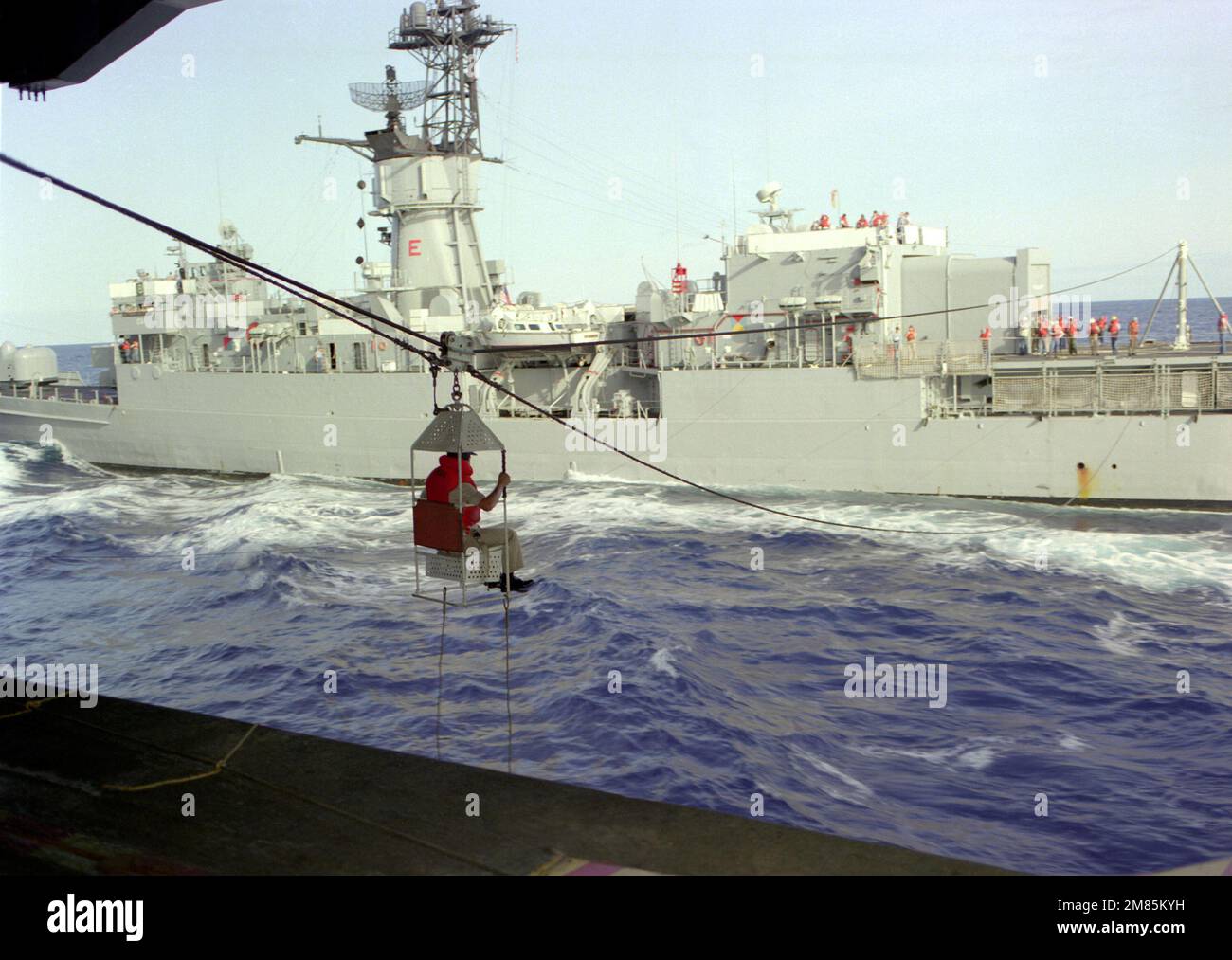A transfer-at-sea chair on a highline rig is used to return a ...