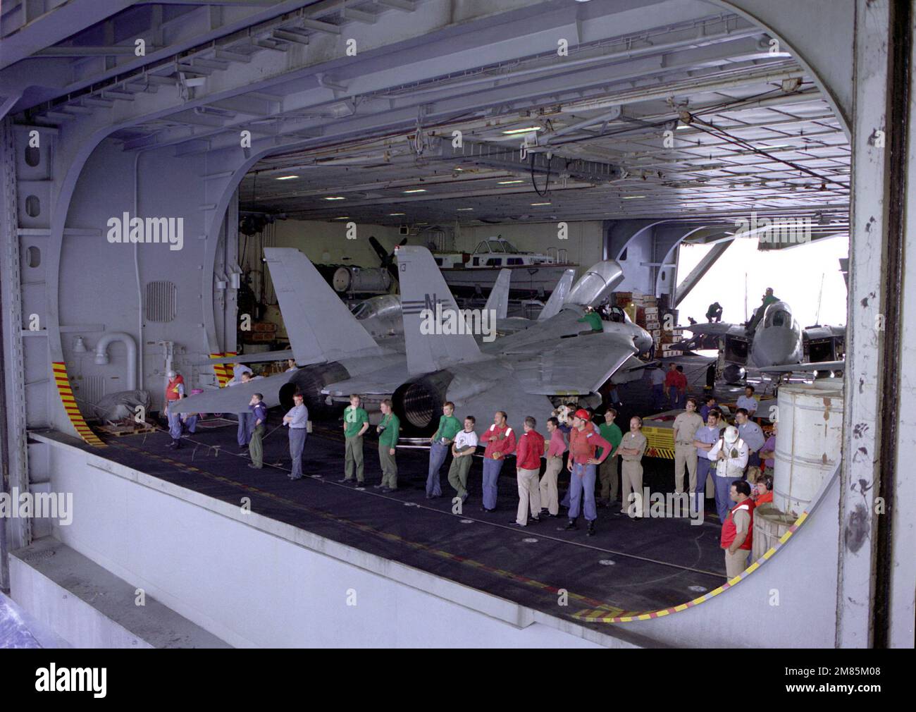 Crewmen watch from the hangar bay of the nuclear-powered aircraft ...