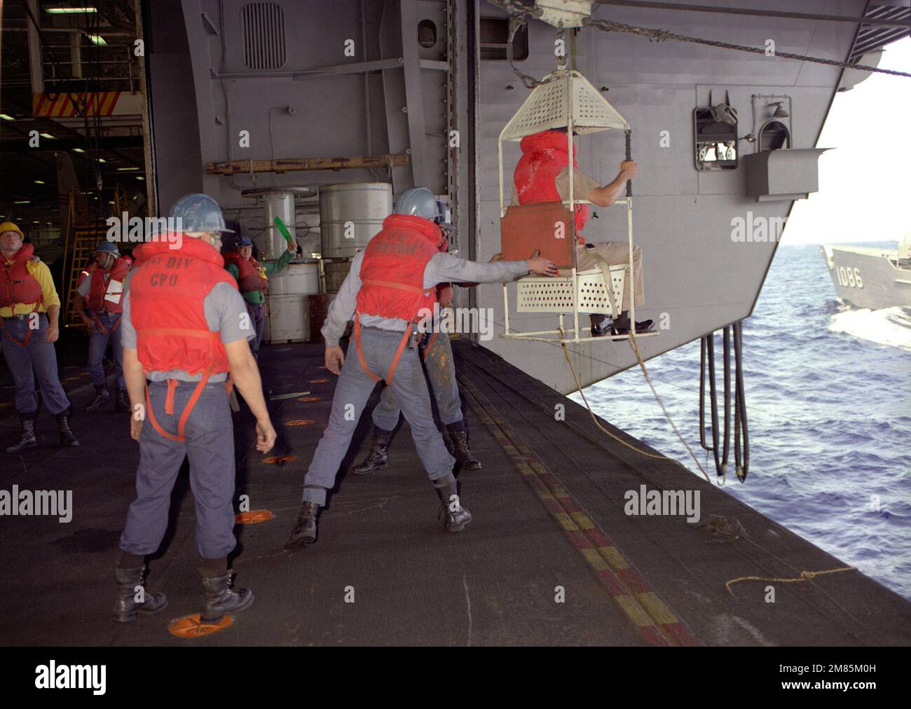 A transfer-at-sea chair on a highline rig is used to return a ...