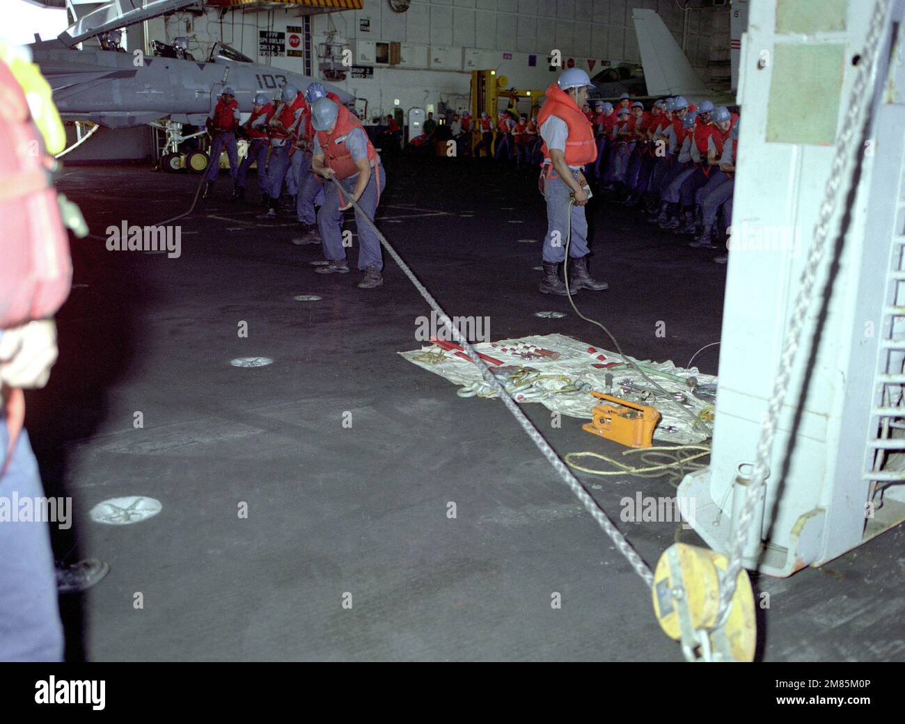 Crew members haul on a line while using a transfer-at-sea chair to ...