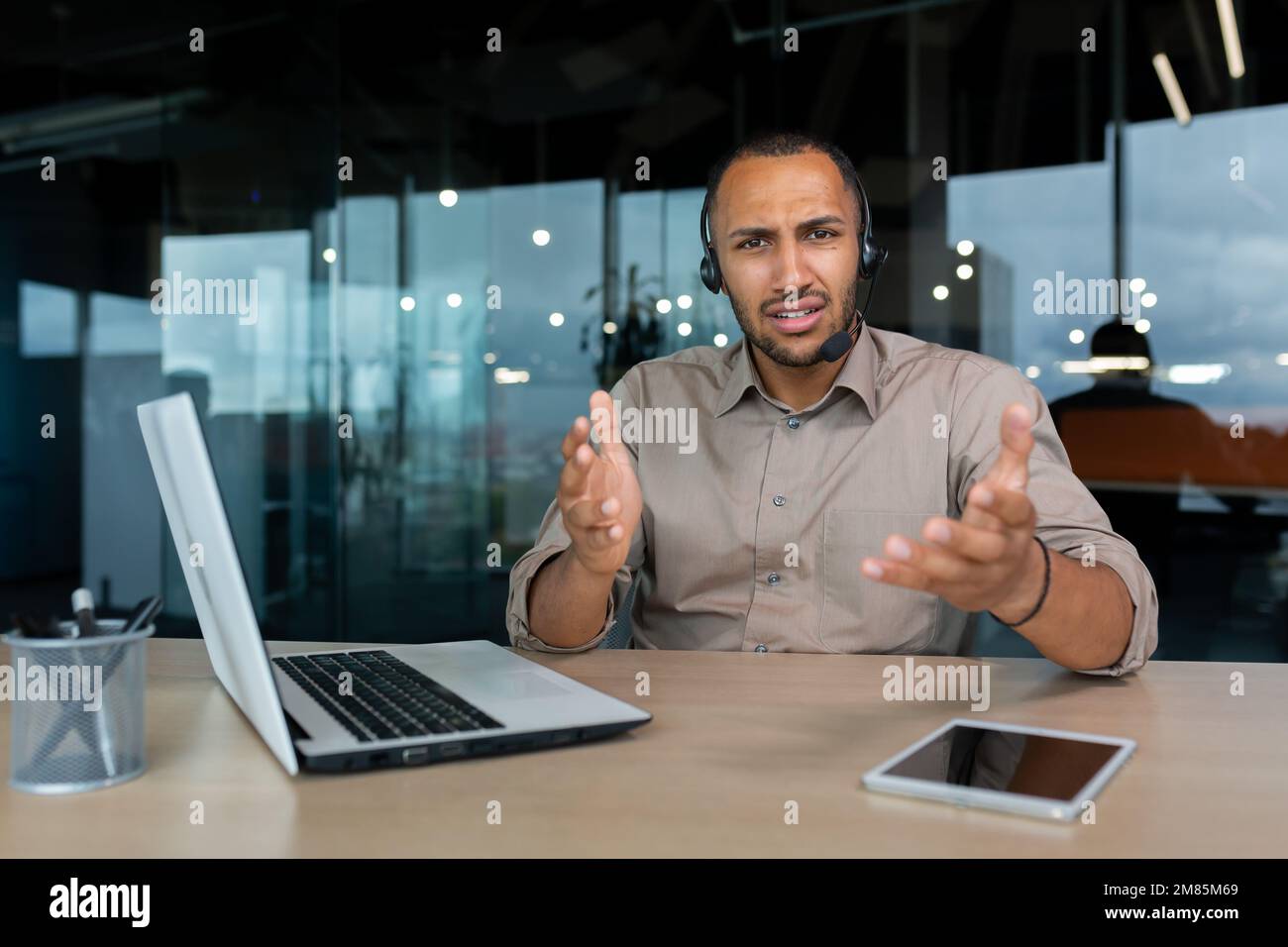 Angry worker with video call headset talking to customer, hispanic man ...