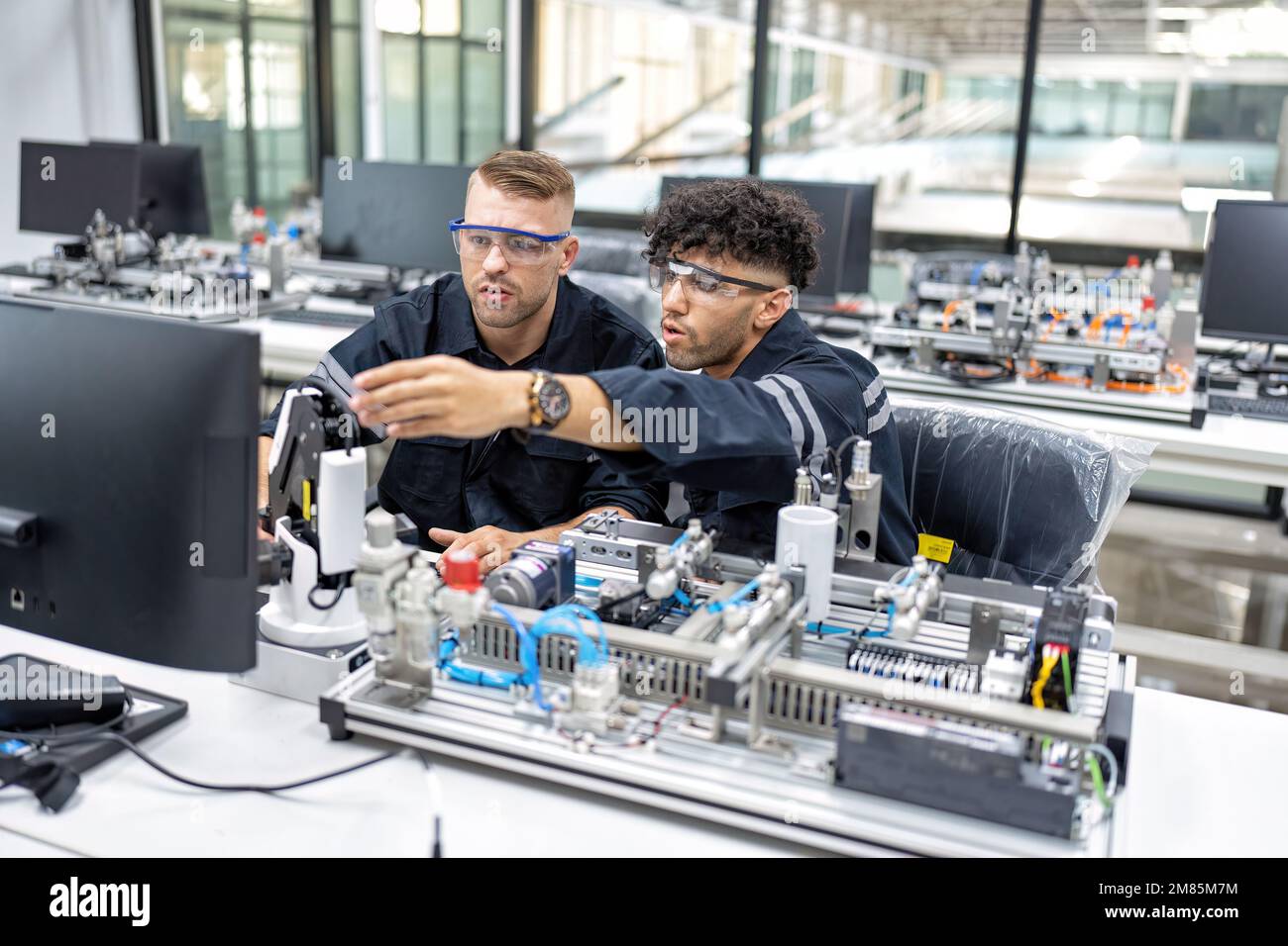 Engineer sitting in robot fabrication room quality checking electronic ...