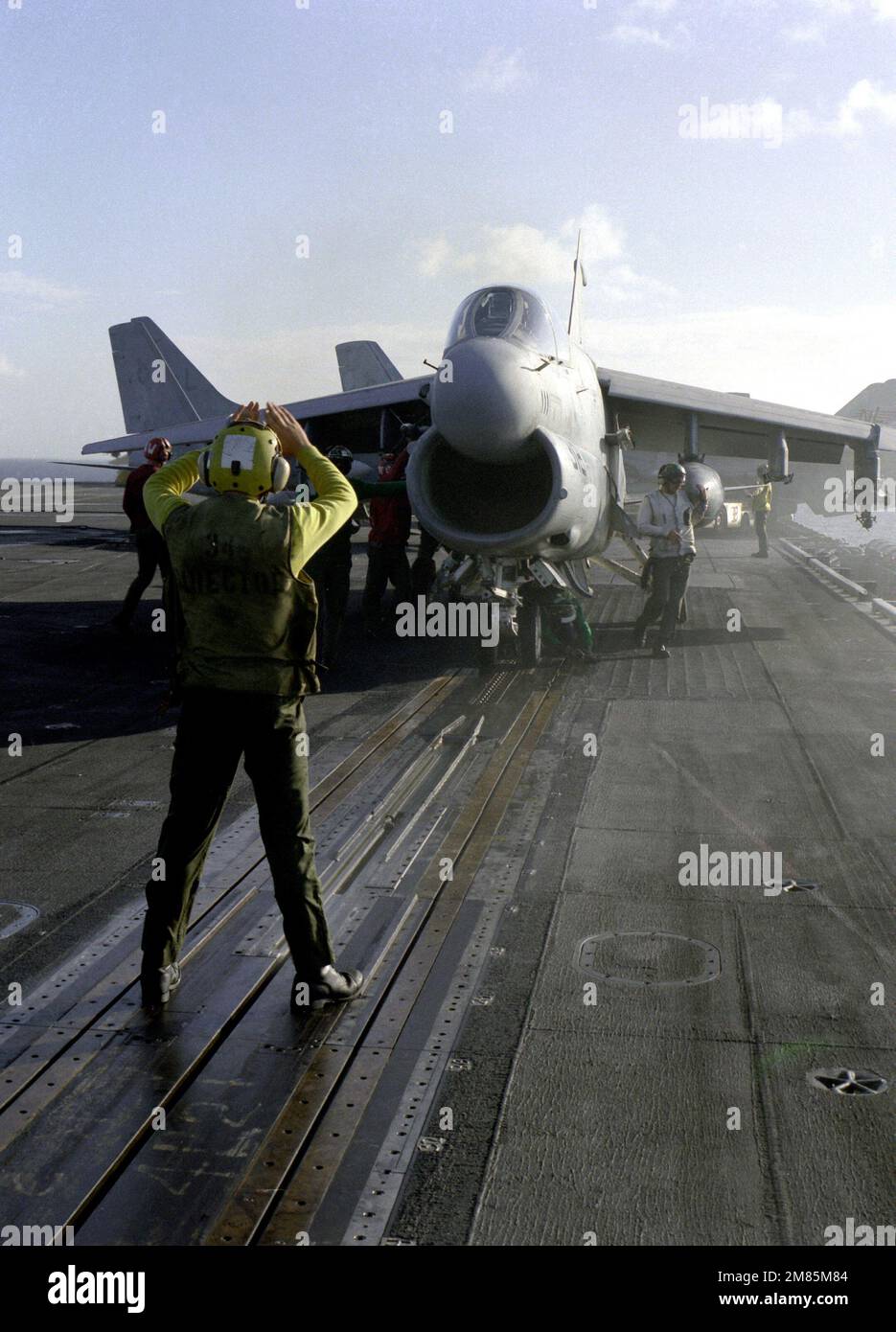 A flight deck crewman directs an A-7E Corsair II aircraft onto a ...