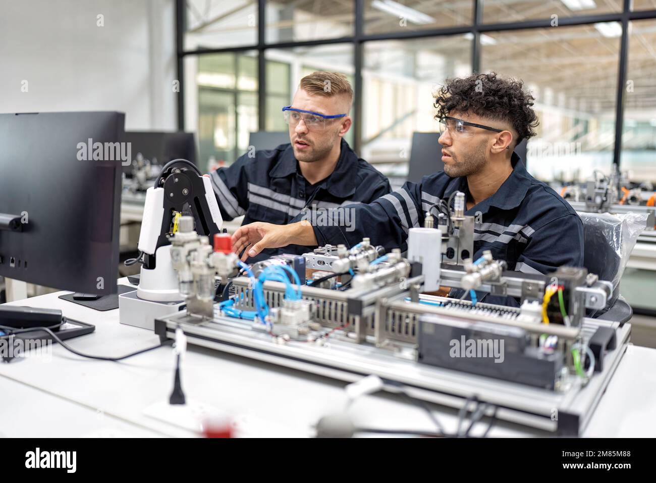 Engineer sitting in robot fabrication room quality checking electronic ...