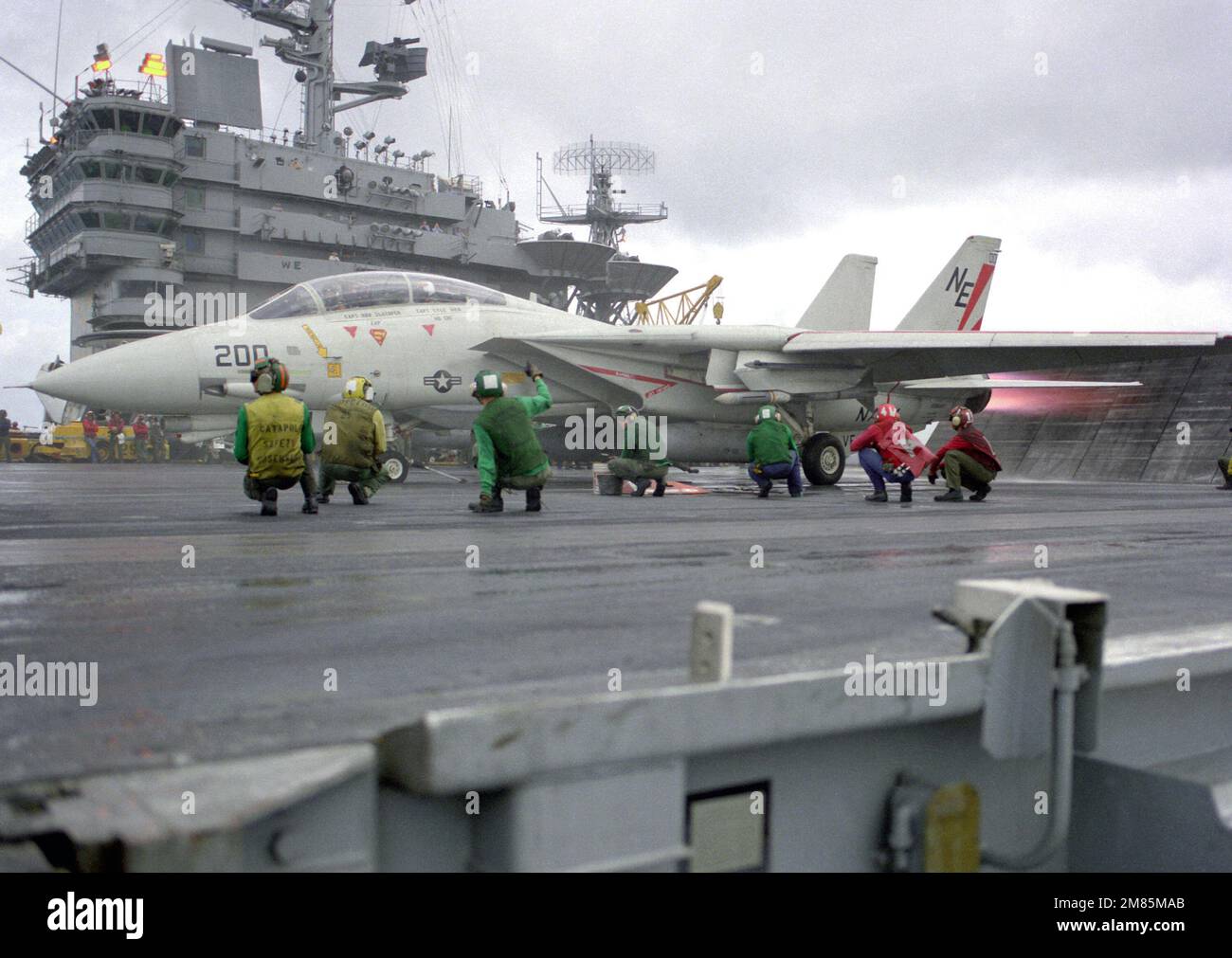 Flight deck crewmen make final preflight checks before launching an F ...