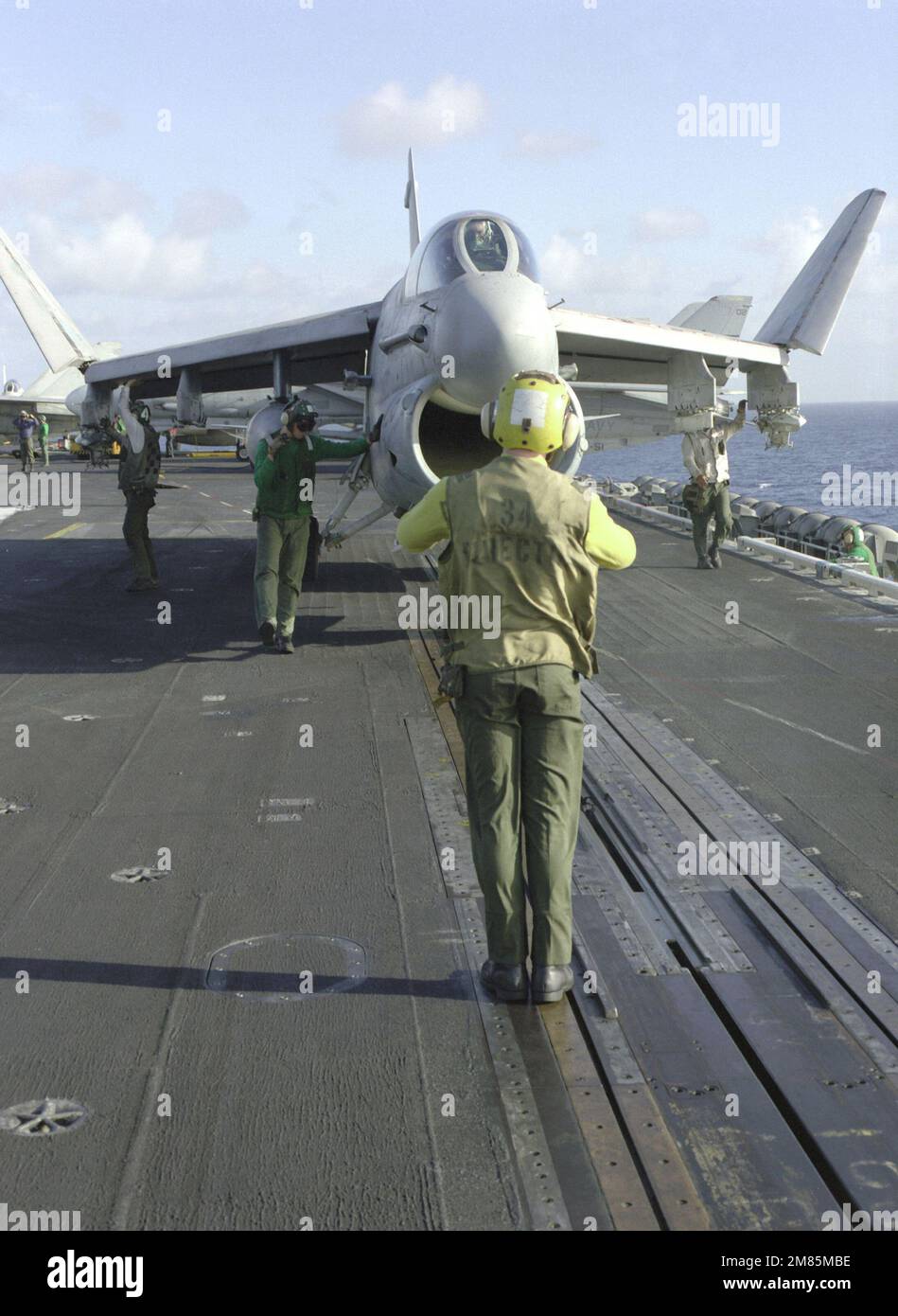 A plane director guides an A-7E Corsair II aircraft into position on a ...