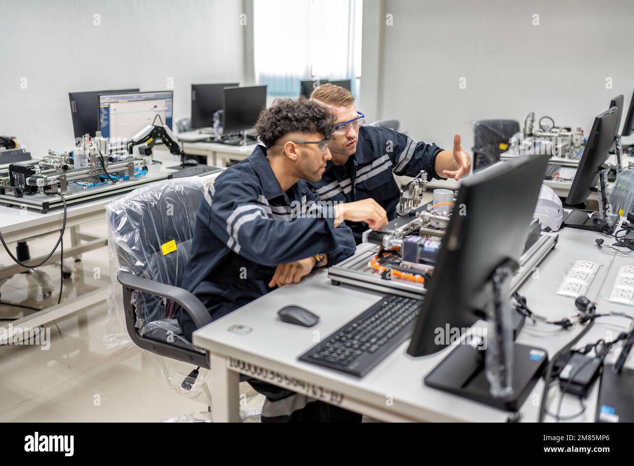 Engineer sitting in robot fabrication room quality checking electronic ...