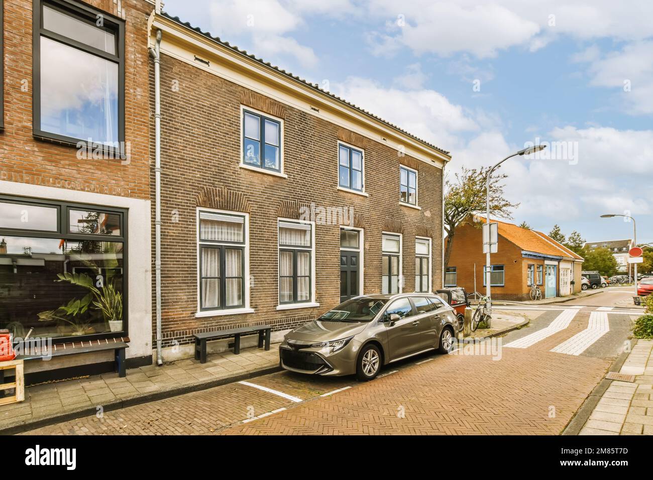 a car parked on the side of a street in front of a brick building with ...