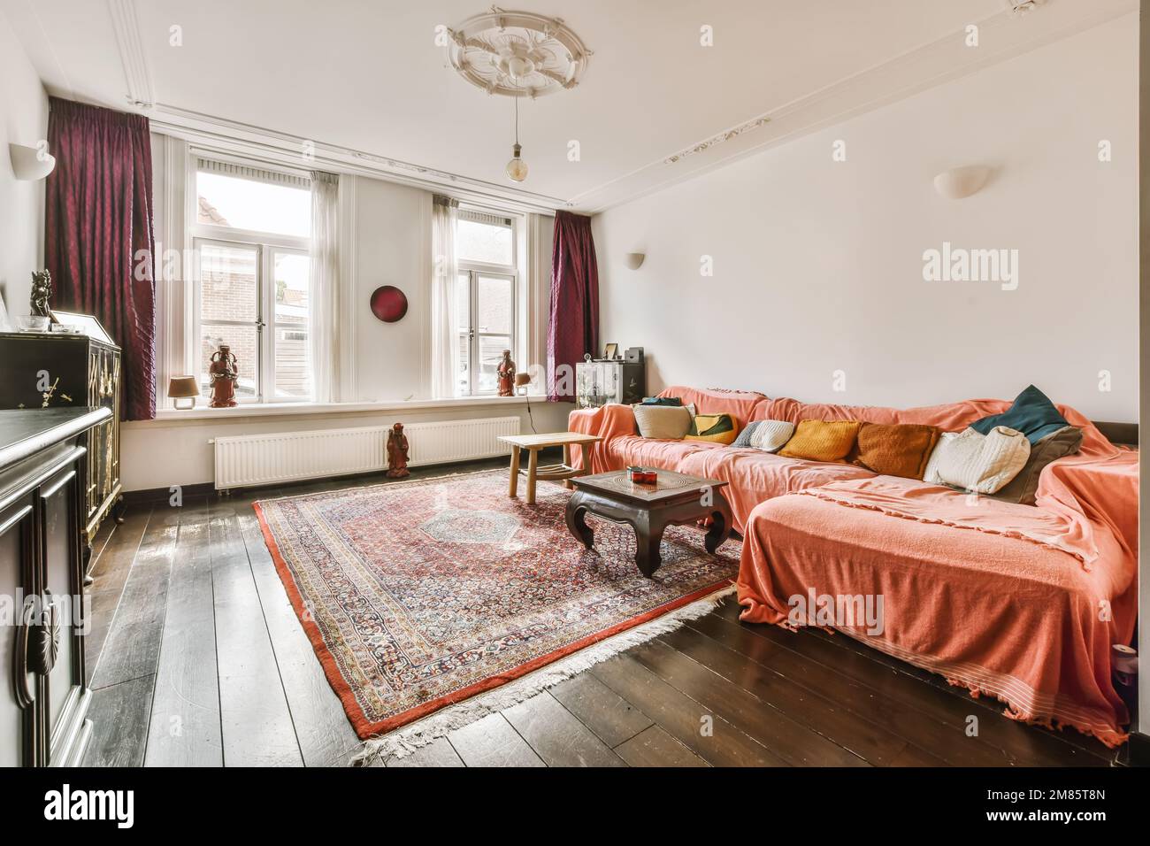 a living room with an orange couch and colorful rugs on the hardwood ...