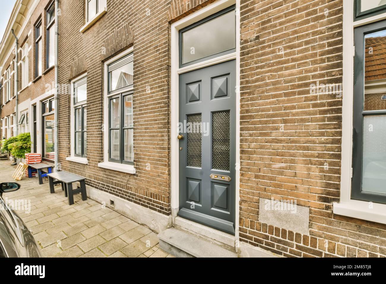 a brick building with windows and a bench on the sidewalk next to an ...