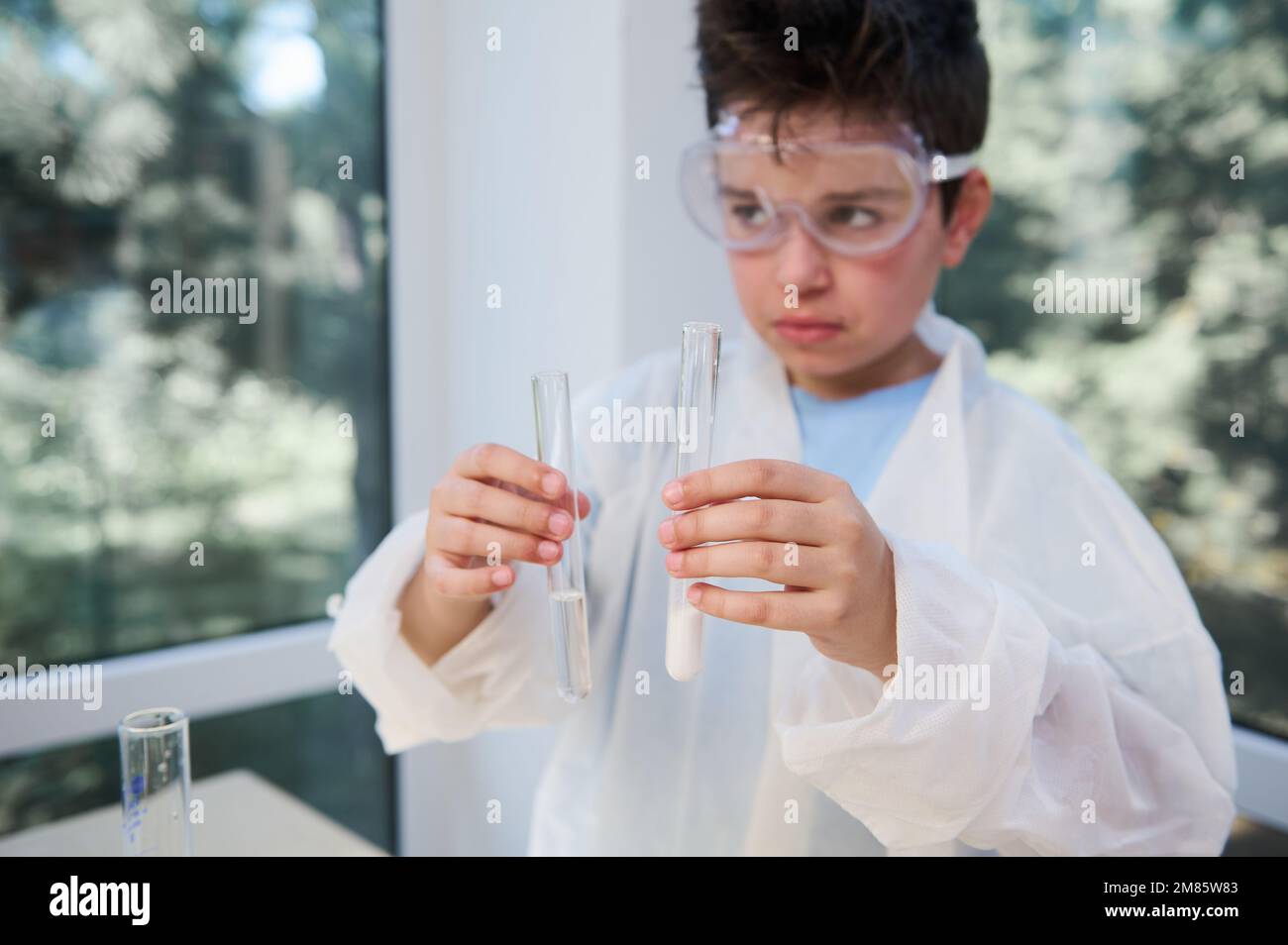 Close-up test tubes with chemicals and reagents in hands of a schoolkid ...